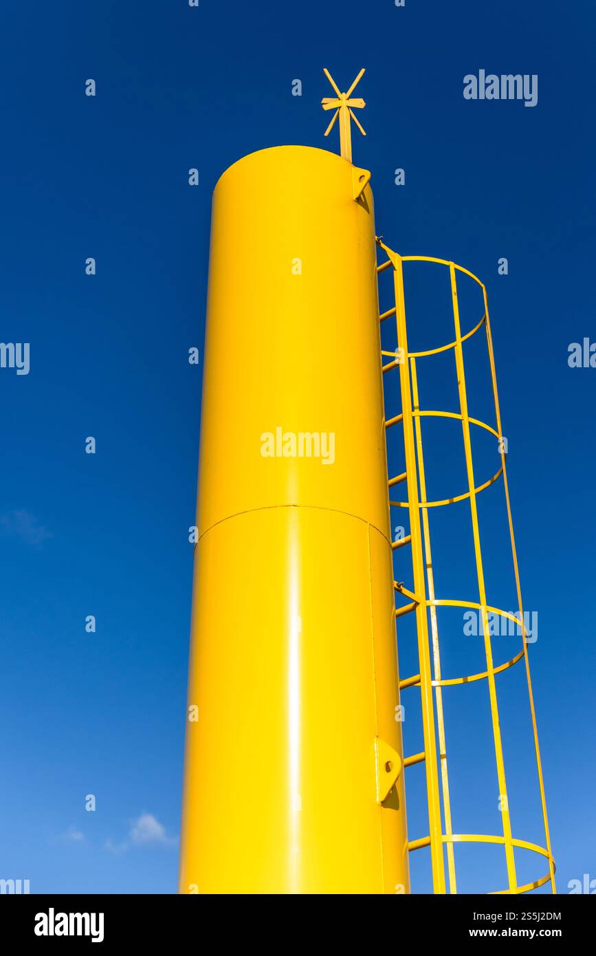 Yellow navigation tower with cross shaped top mark is under blue sky ...
