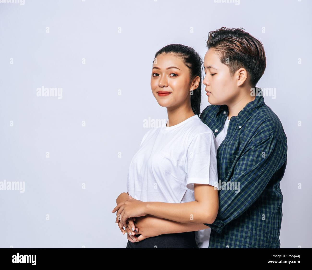 Two female lovers standing and hugging from behind Stock Photo - Alamy