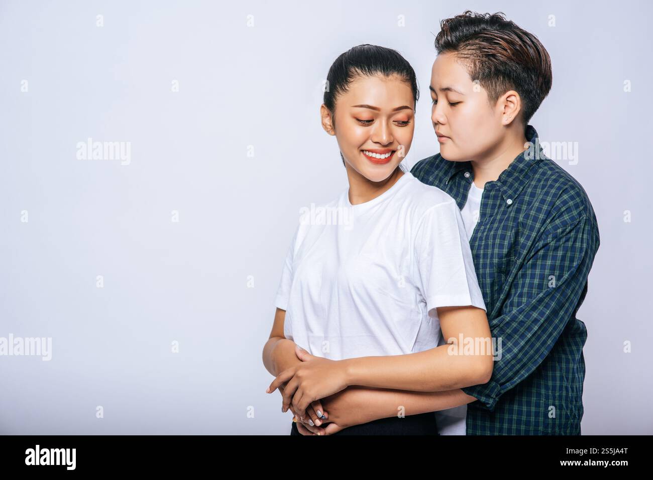 Two female lovers standing and hugging from behind Stock Photo - Alamy