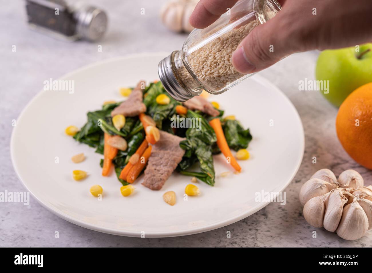 Hand holding a bottle of white sesame pouring food. Selective focus ...