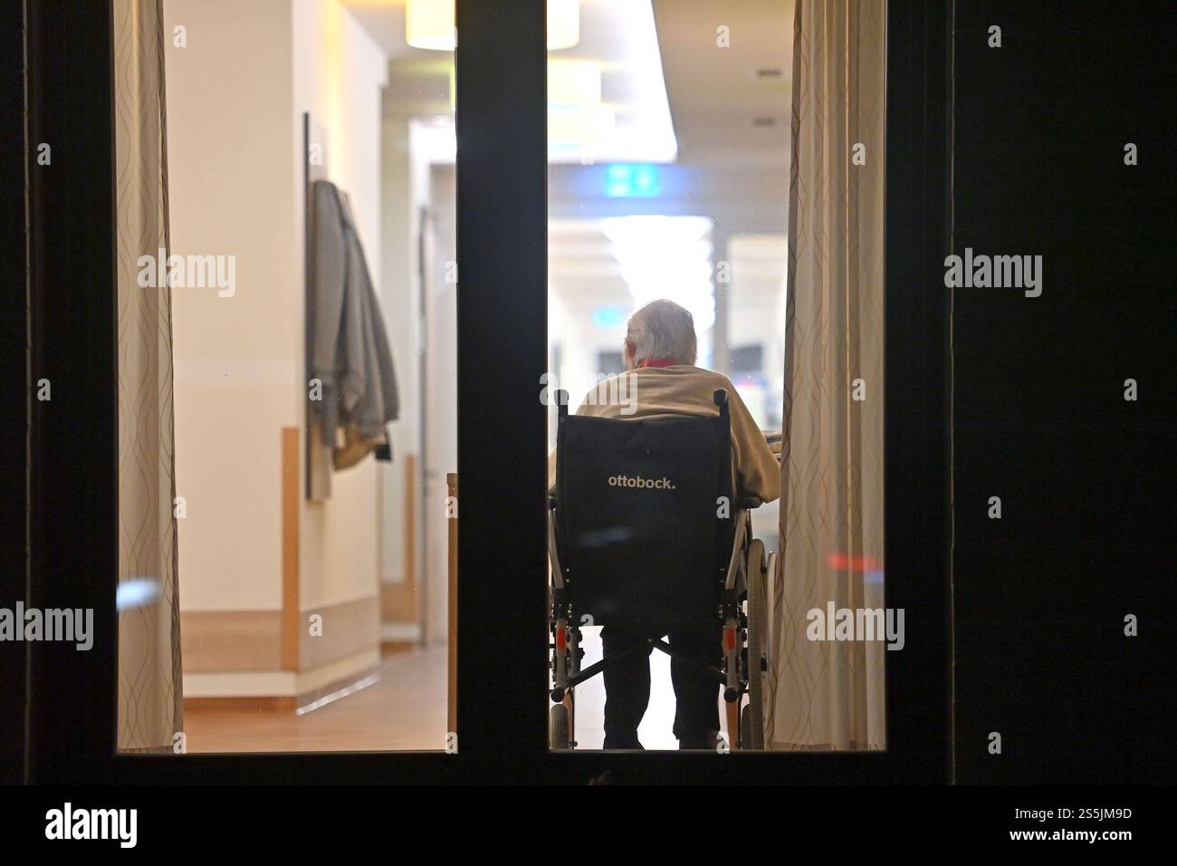 Blick auf eine Person im Rollstuhl in einem Flur in einem Altenheim im Landkreis Muenchen Stock ...