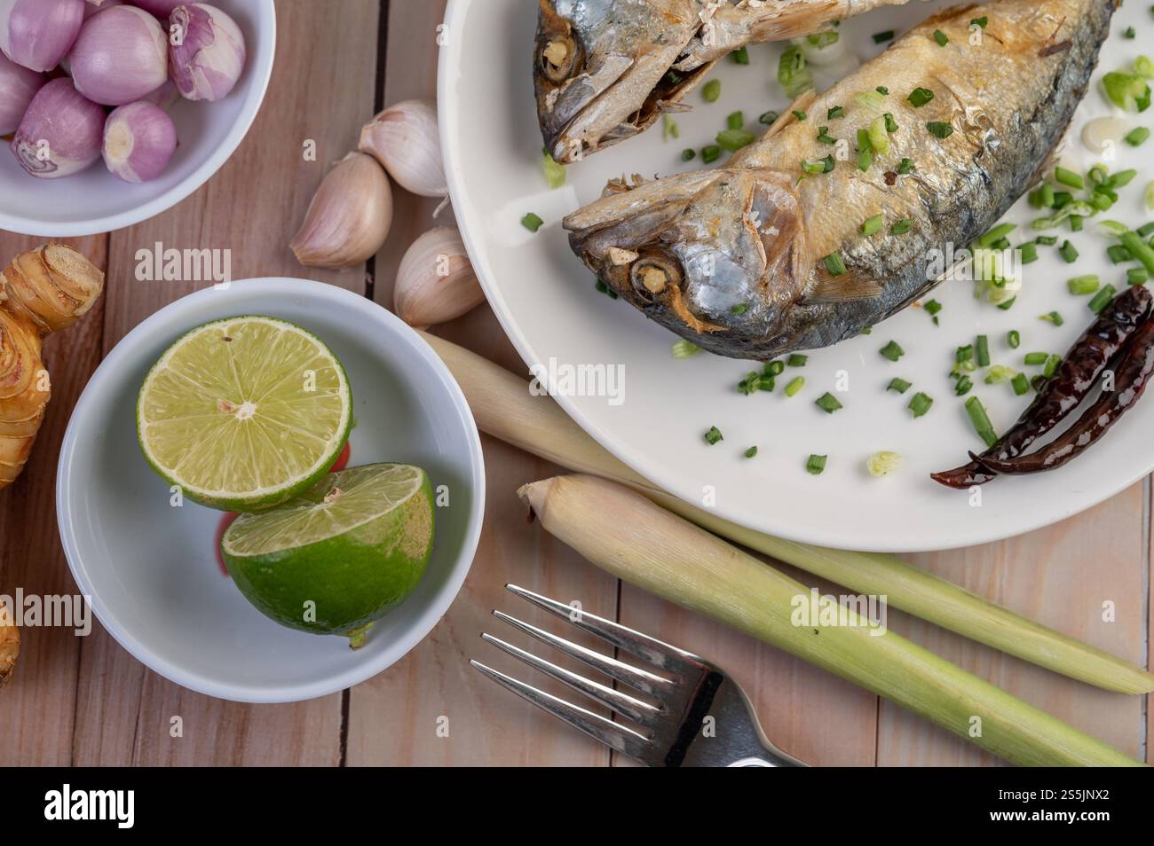 Two cooked mackerel, placed in a white dish, sprinkled with spring ...