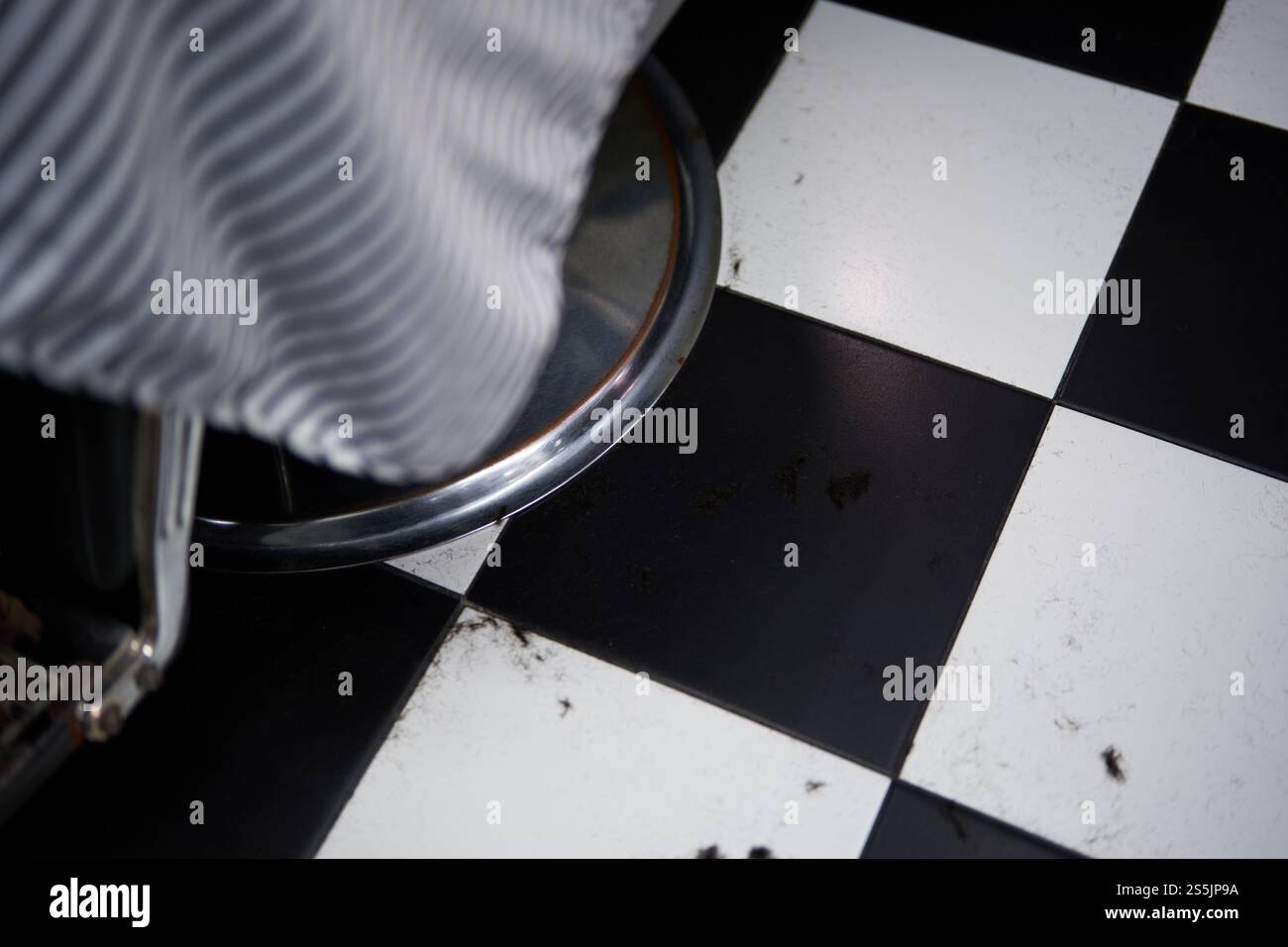 Black and white checkerboard floor with dirty spots near a metal stool ...