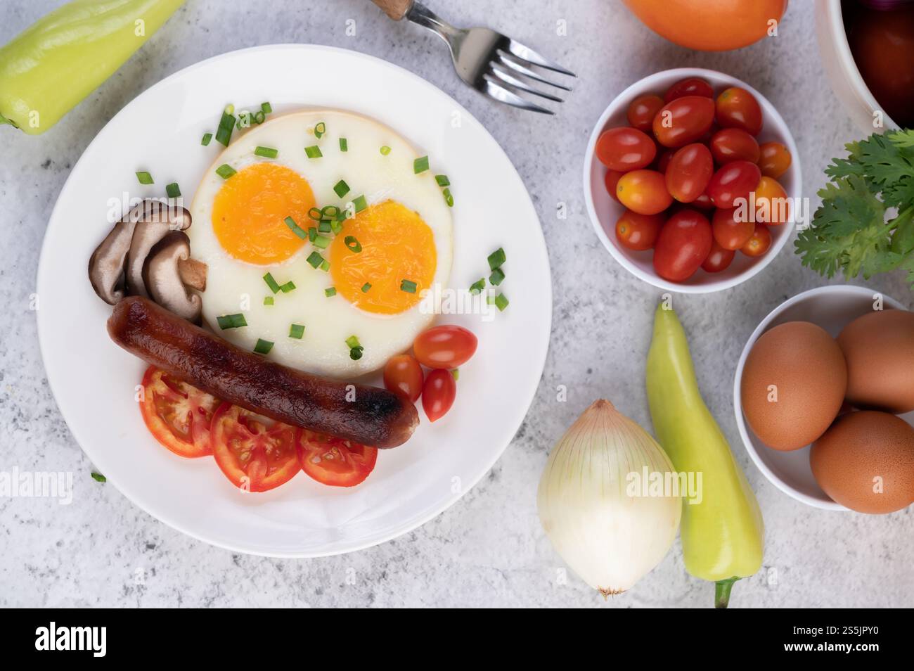 Breakfast consisting of bread, fried eggs, tomatoes, Chinese sausage ...
