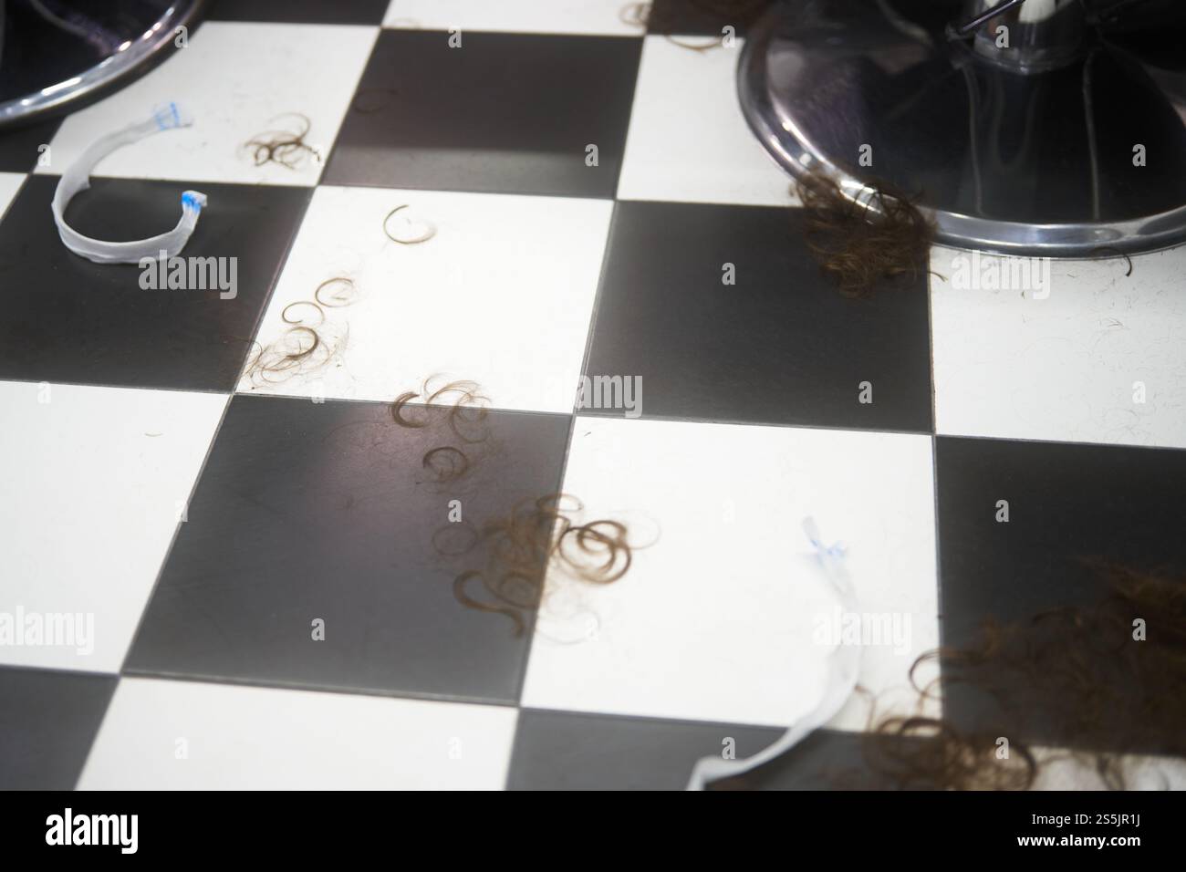 Hair clippings scattered across a black and white checkered salon floor ...