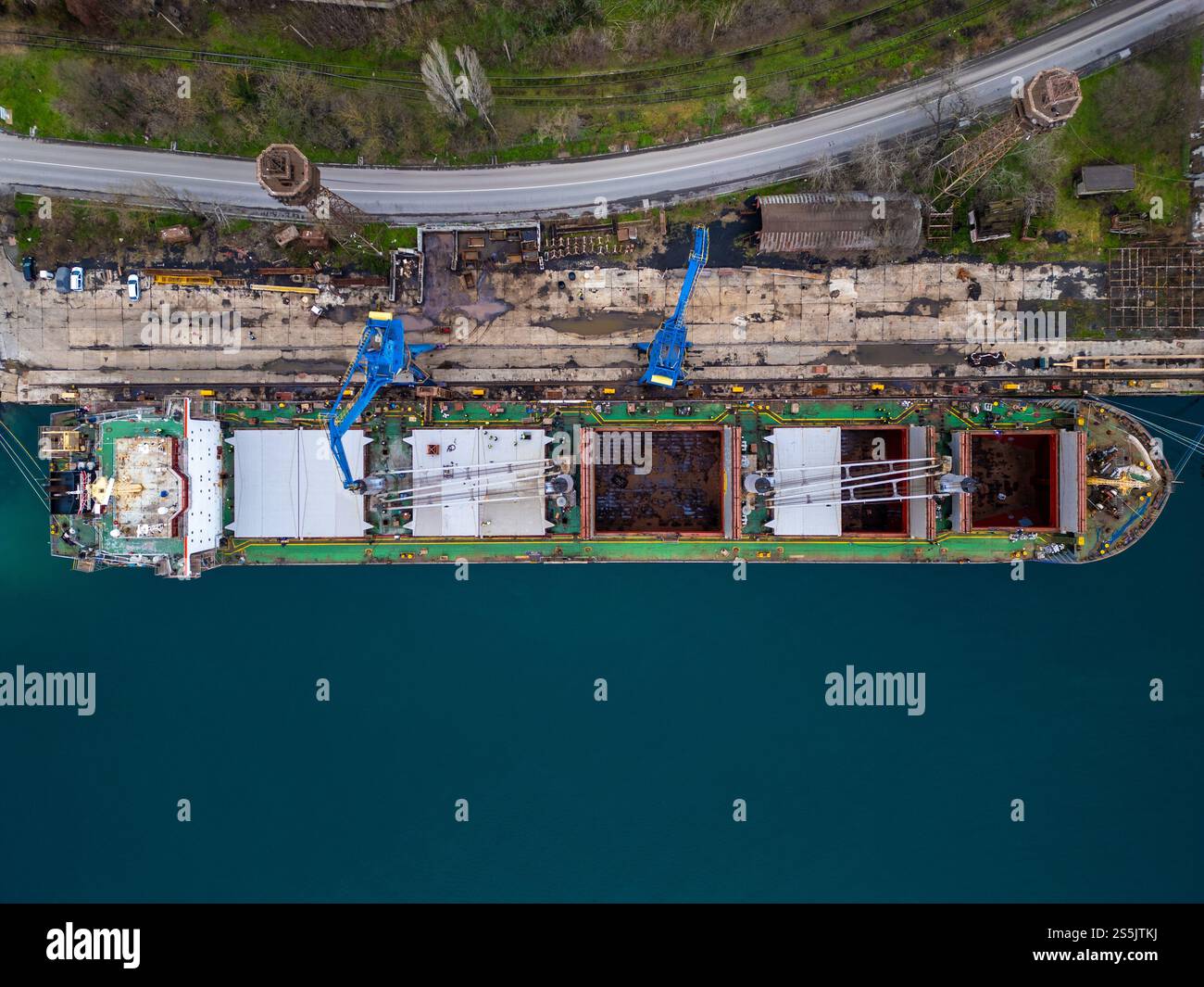 Aerial top-down view of a cargo ship being loaded at an industrial ...