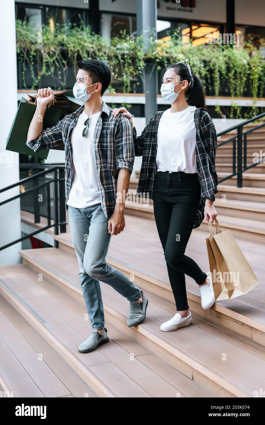 Young couple in protection mask holding multiple paper shopping bag on ...