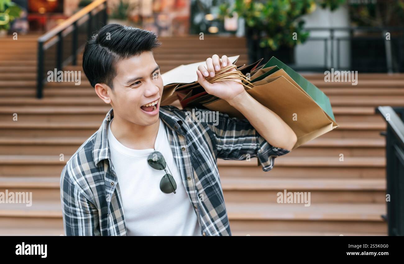 Portrait Handsome young man grinning as he holds a paper bag and shows ...