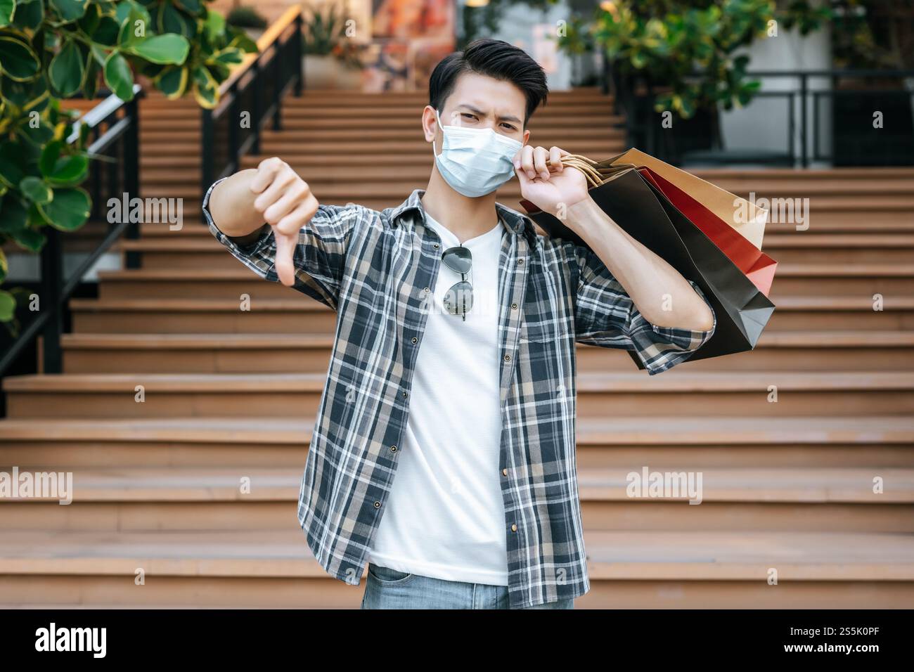Handsome young man in protection mask holds multiple paper bag and ...