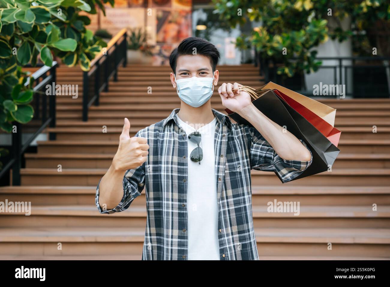 Handsome young man in protection mask holds multiple paper bag and ...