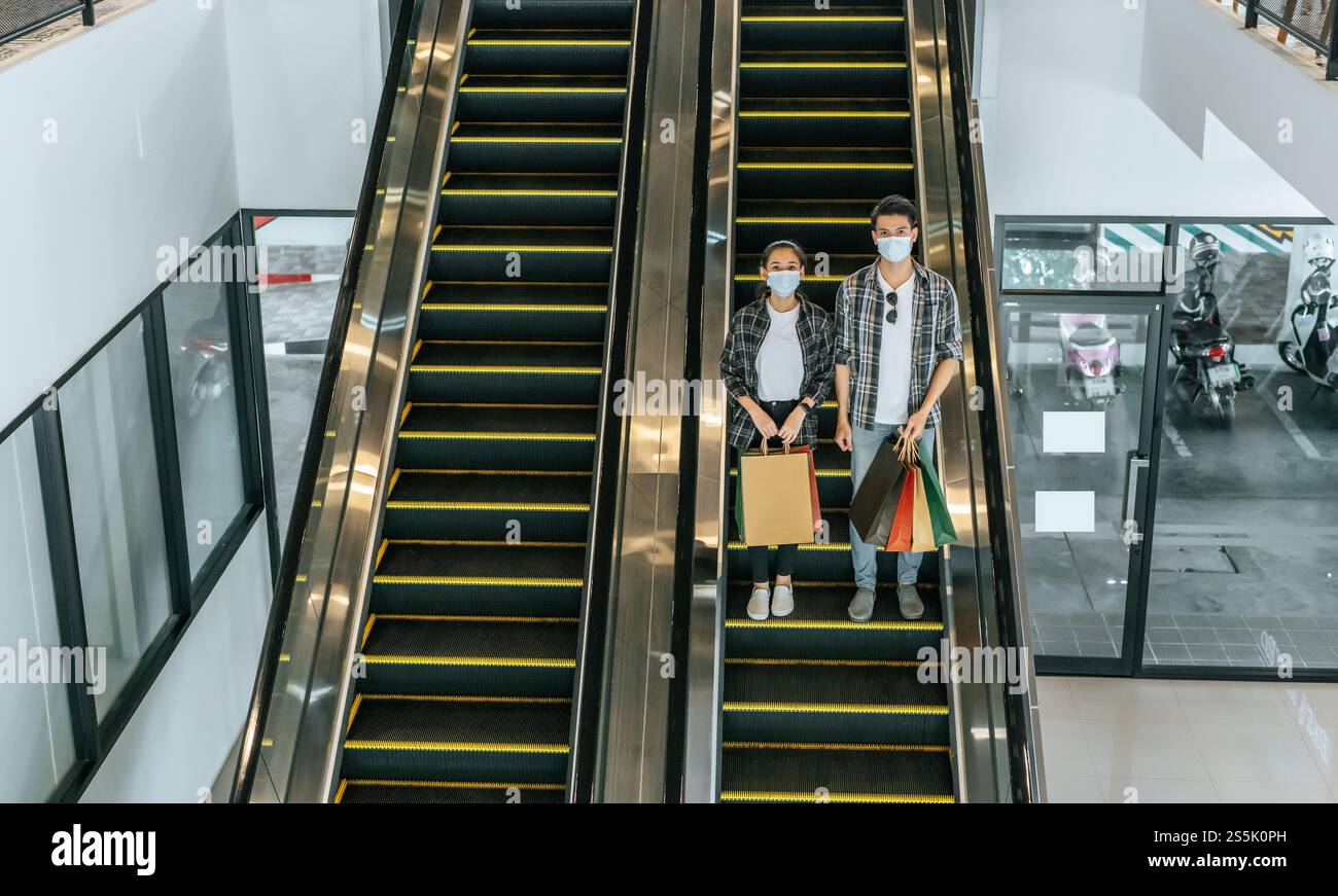 Top view, Young couple holding multiple shopping paper bag on escalator ...