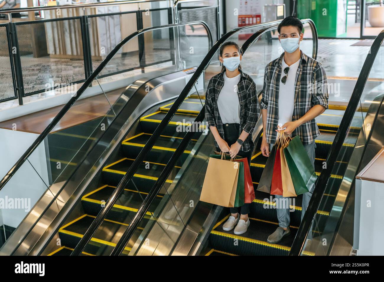 Young couple holding multiple shopping paper bag on escalator in ...