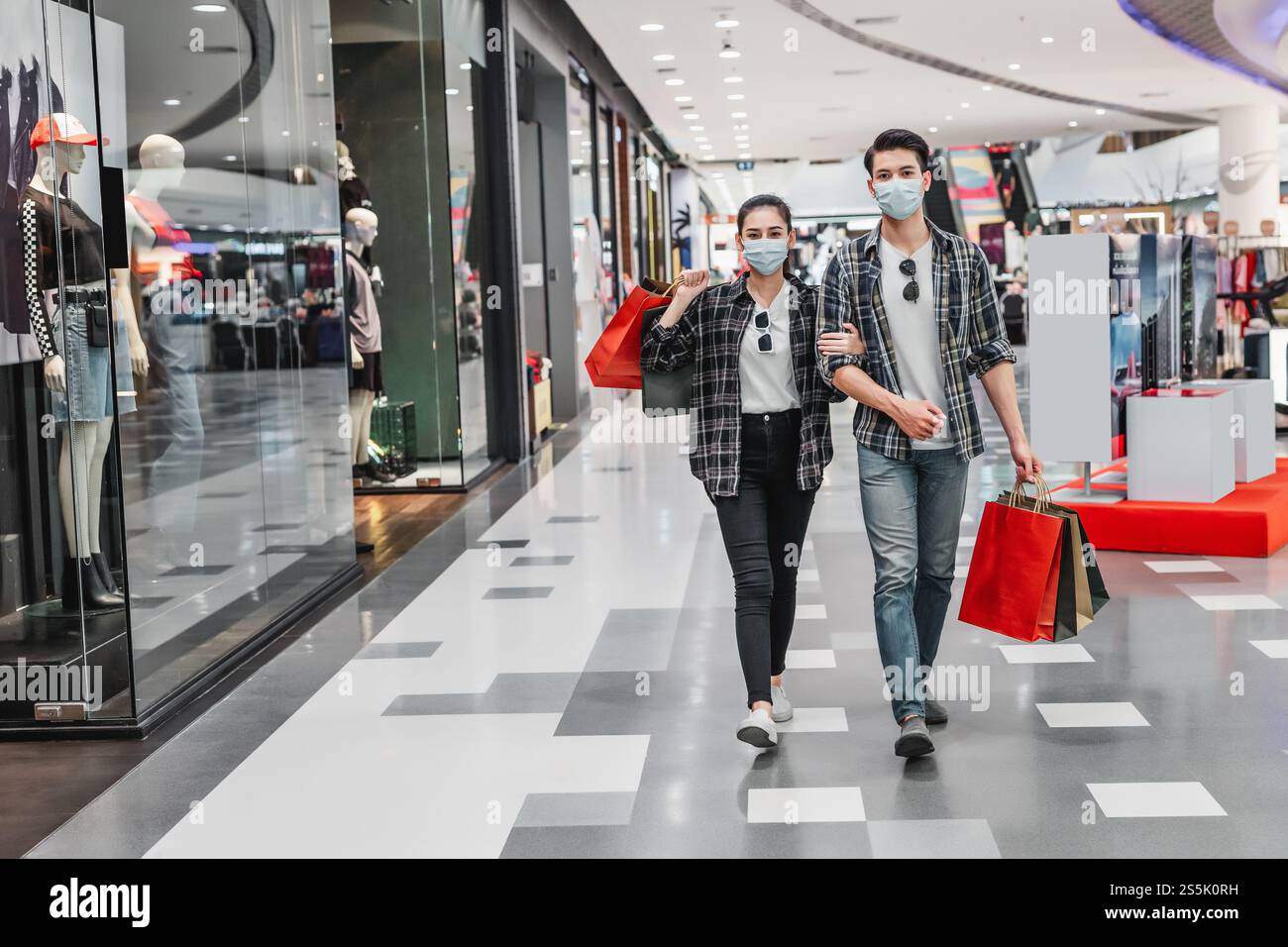 Young couple in protection mask holding multiple paper shopping bag ...