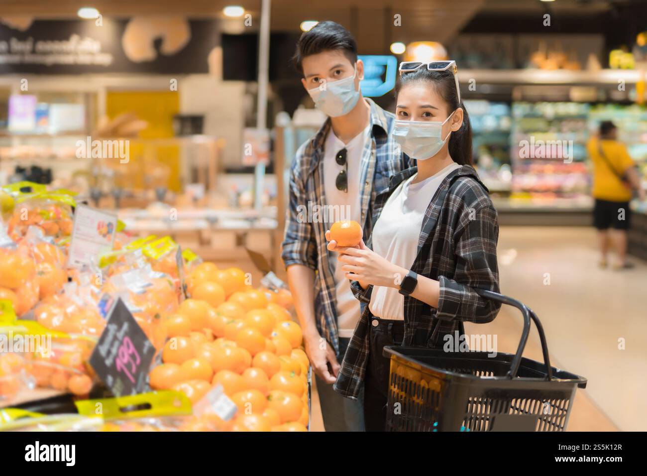 Asian Young Couple in protection mask standing and choose fresh orange ...