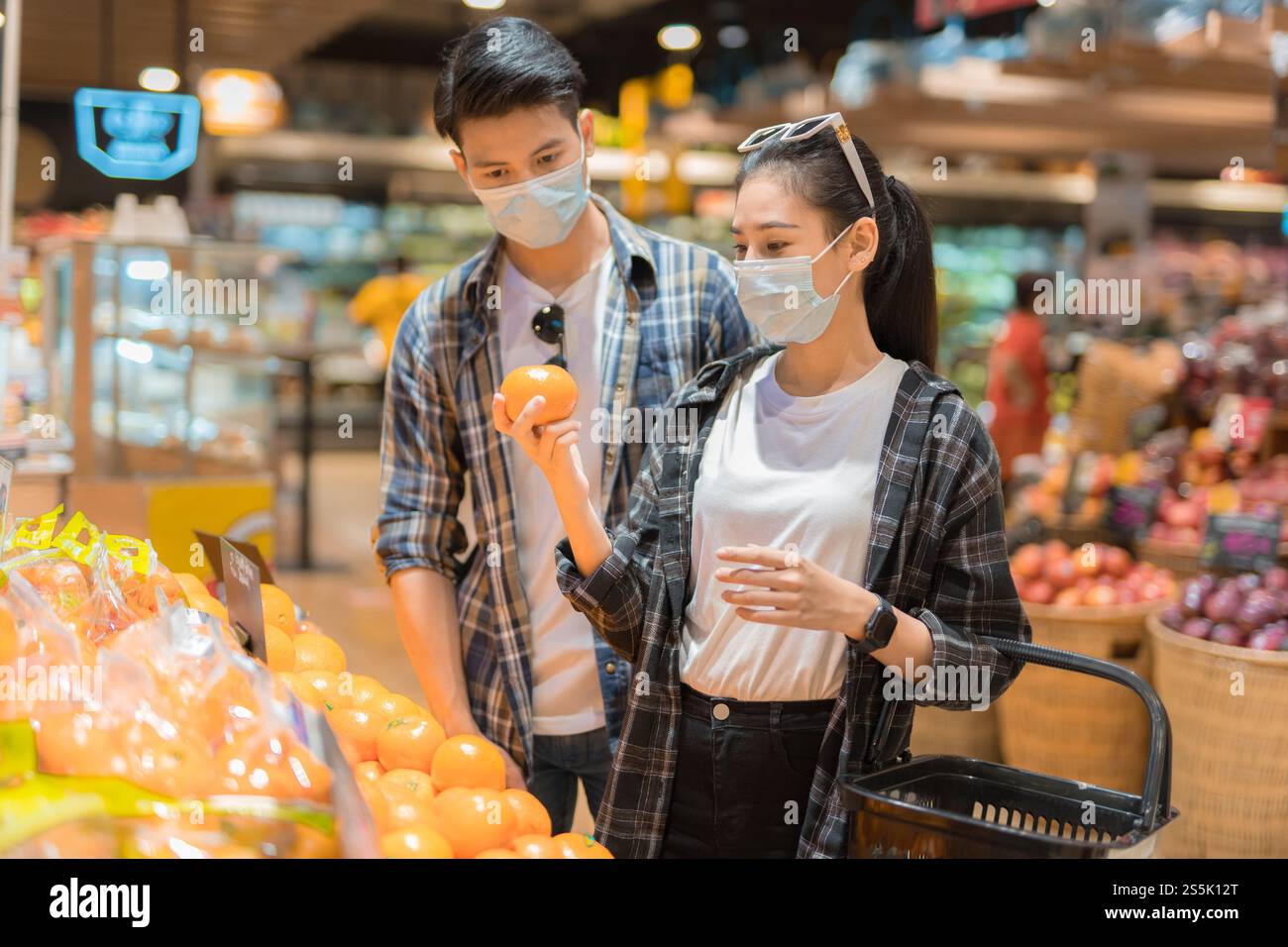 Asian Young Couple in protection mask standing and choose fresh orange ...