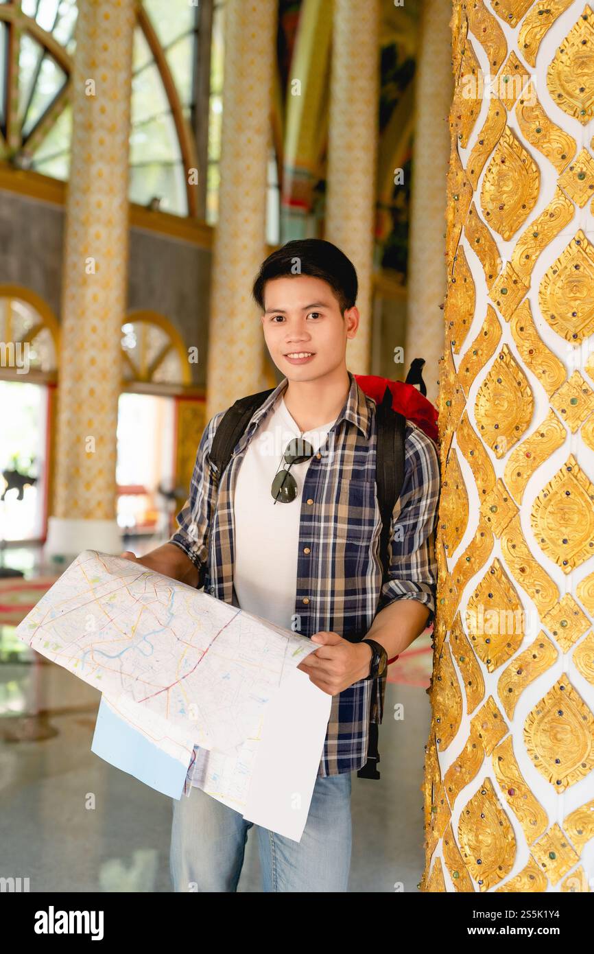 Portrait Young Asian backpacker male standing and checking direction on ...