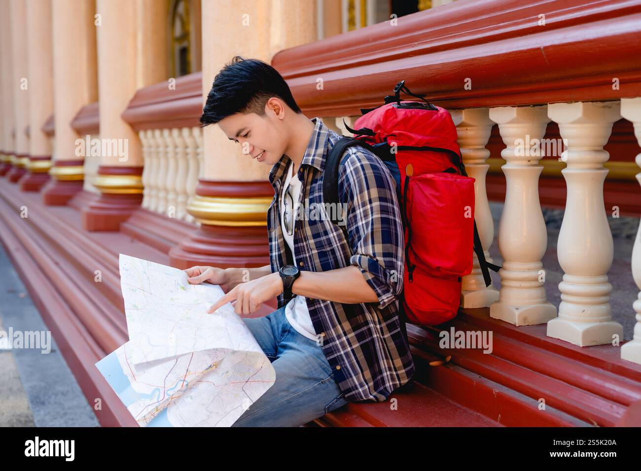 Portrait Young Asian backpacker male sitting and use finger point on ...