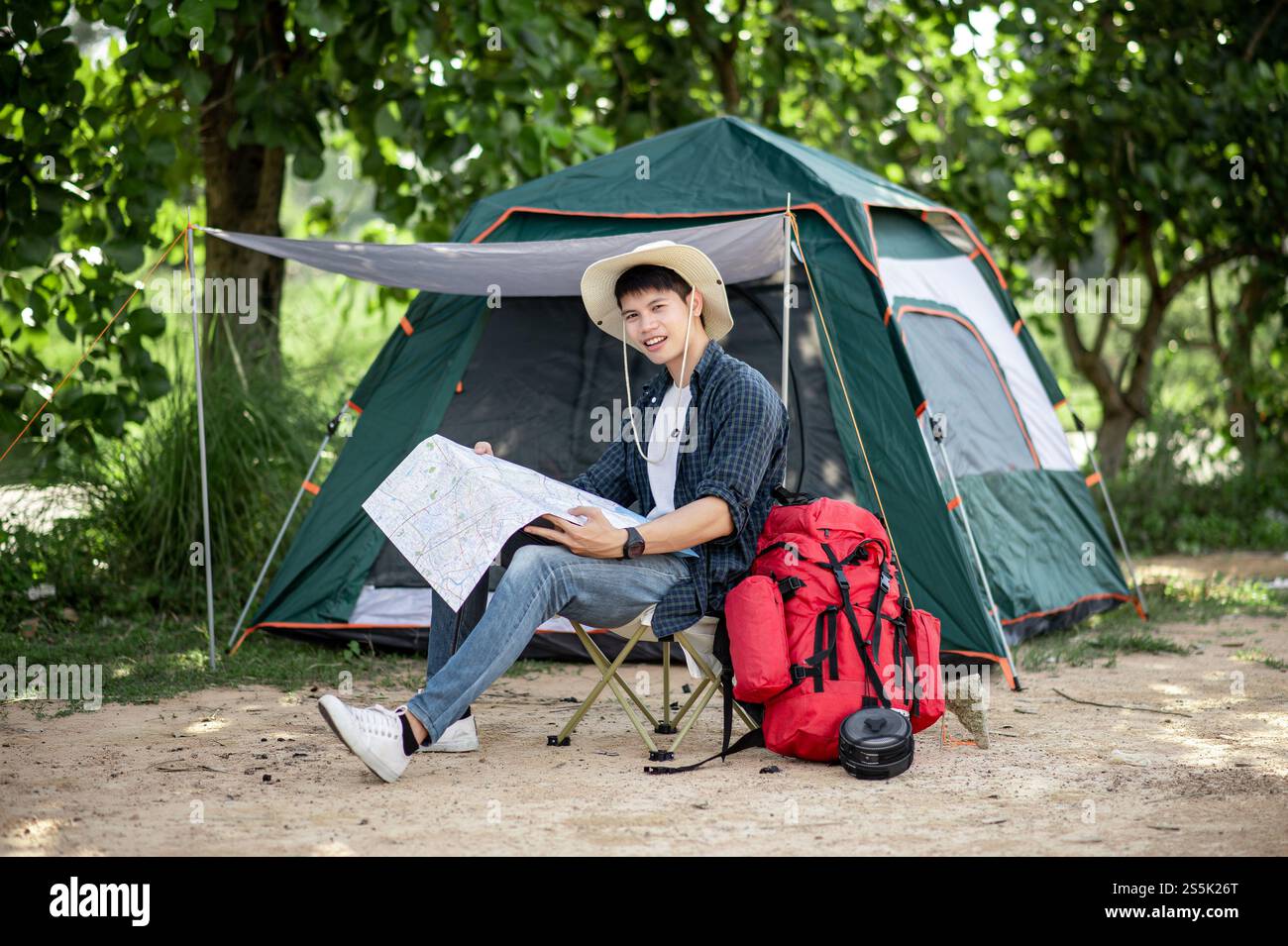 Young backpacker man wearing hat sitting at front of tent in nature ...