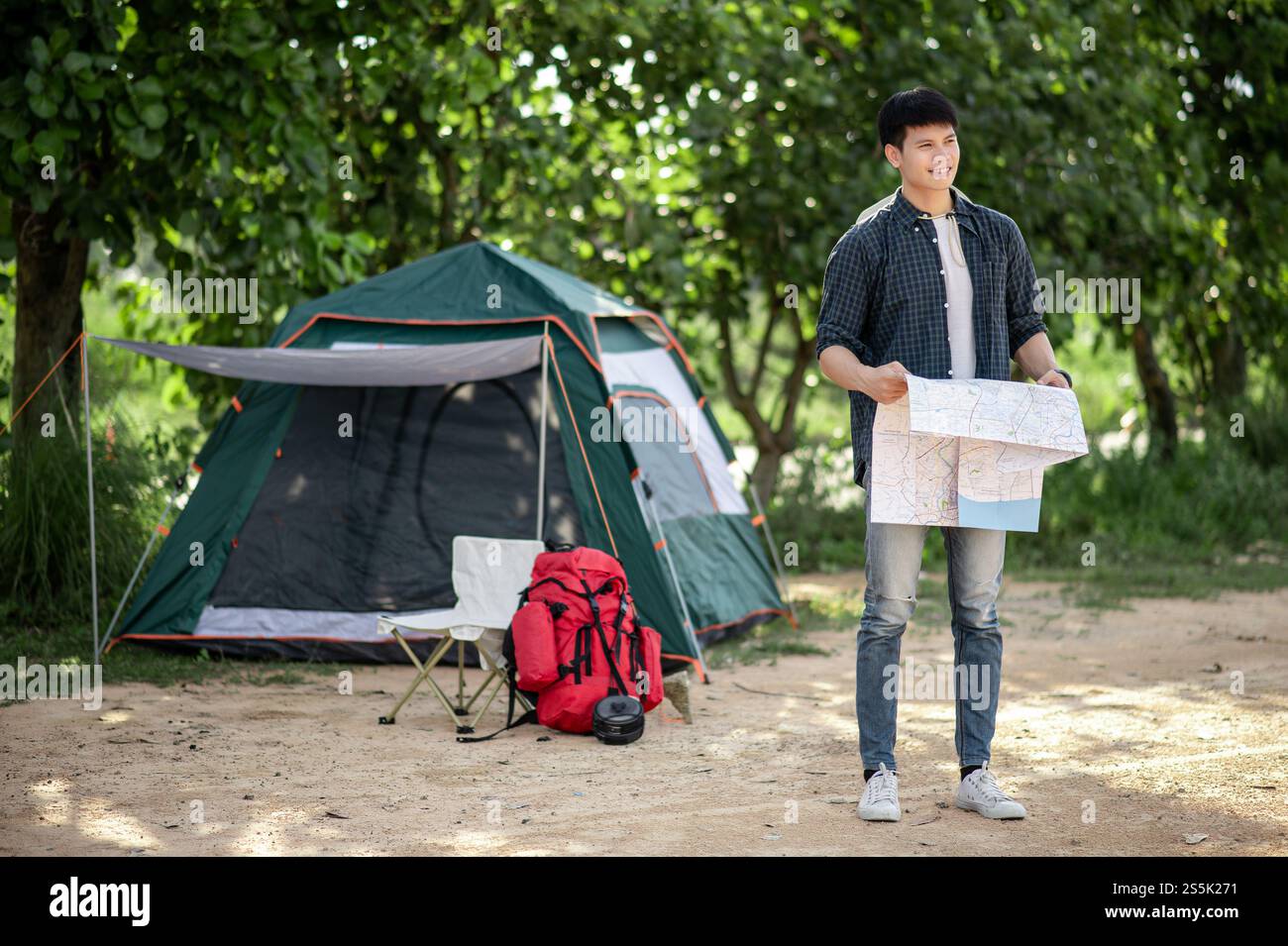 Young backpacker man standing and hold paper map in hand at front of ...