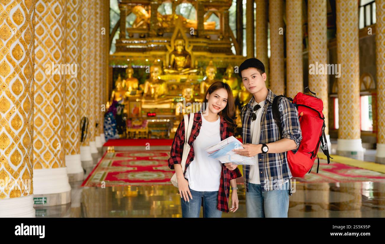 Happy Asian couple tourist backpackers holding paper map while ...