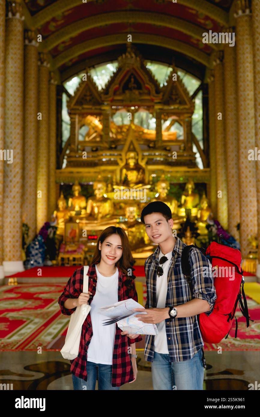 Happy Asian couple tourist backpackers holding paper map while ...