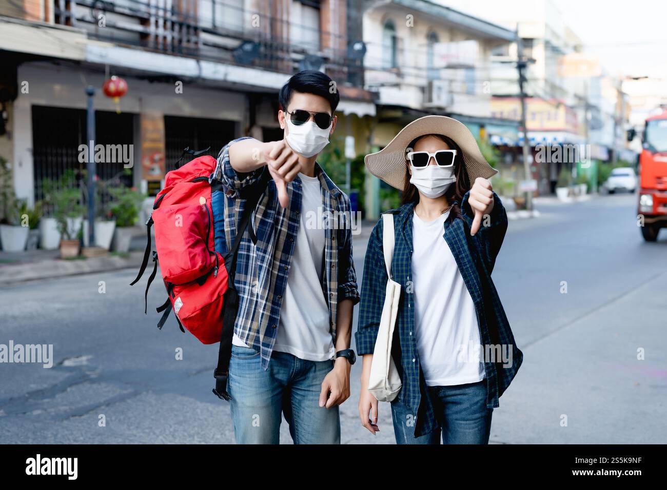 Young backpacker couple in face mask and sunglasses make a prohibition ...