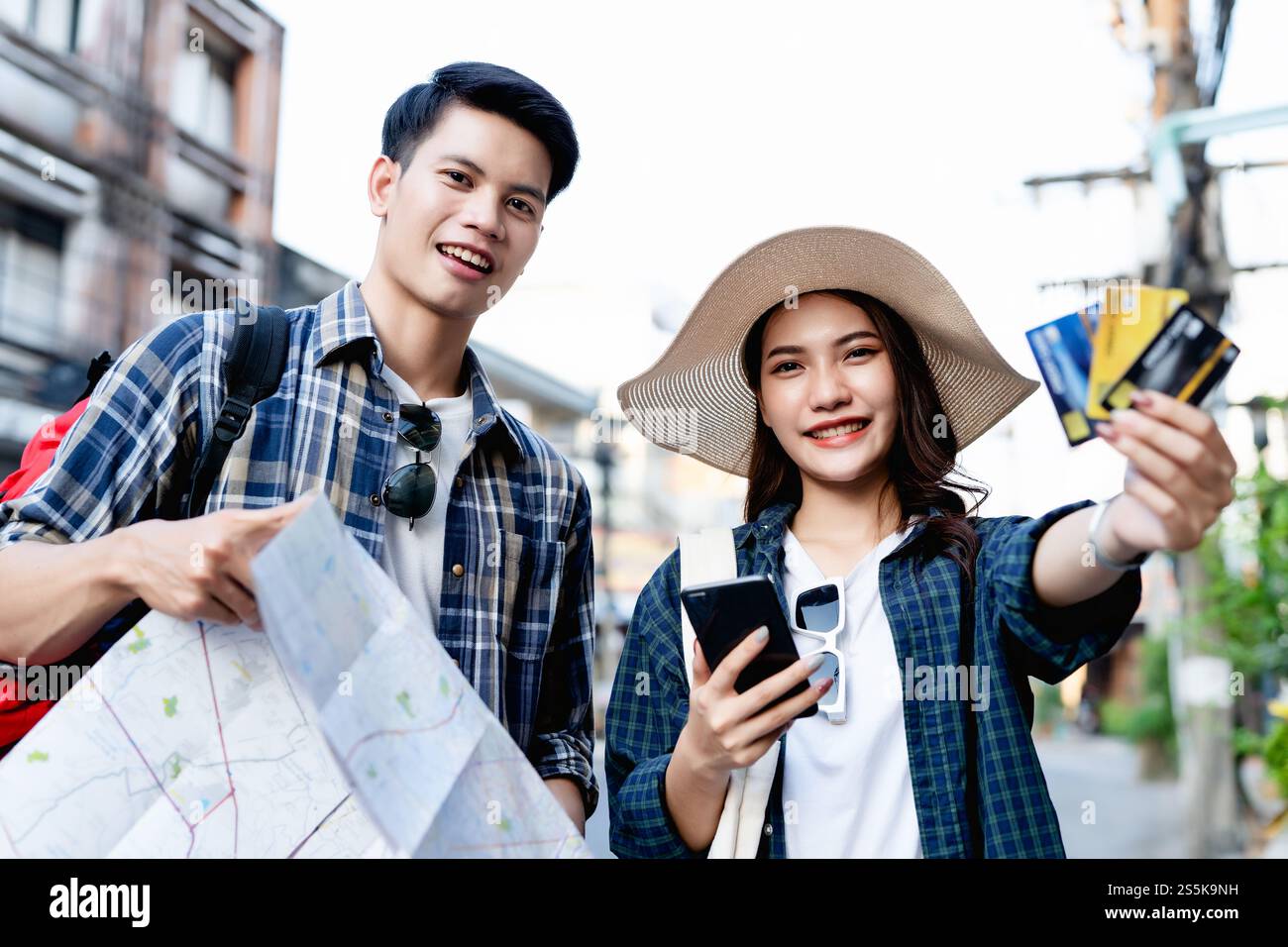 Young backpacker man holding paper map and pretty woman wear sombrero ...