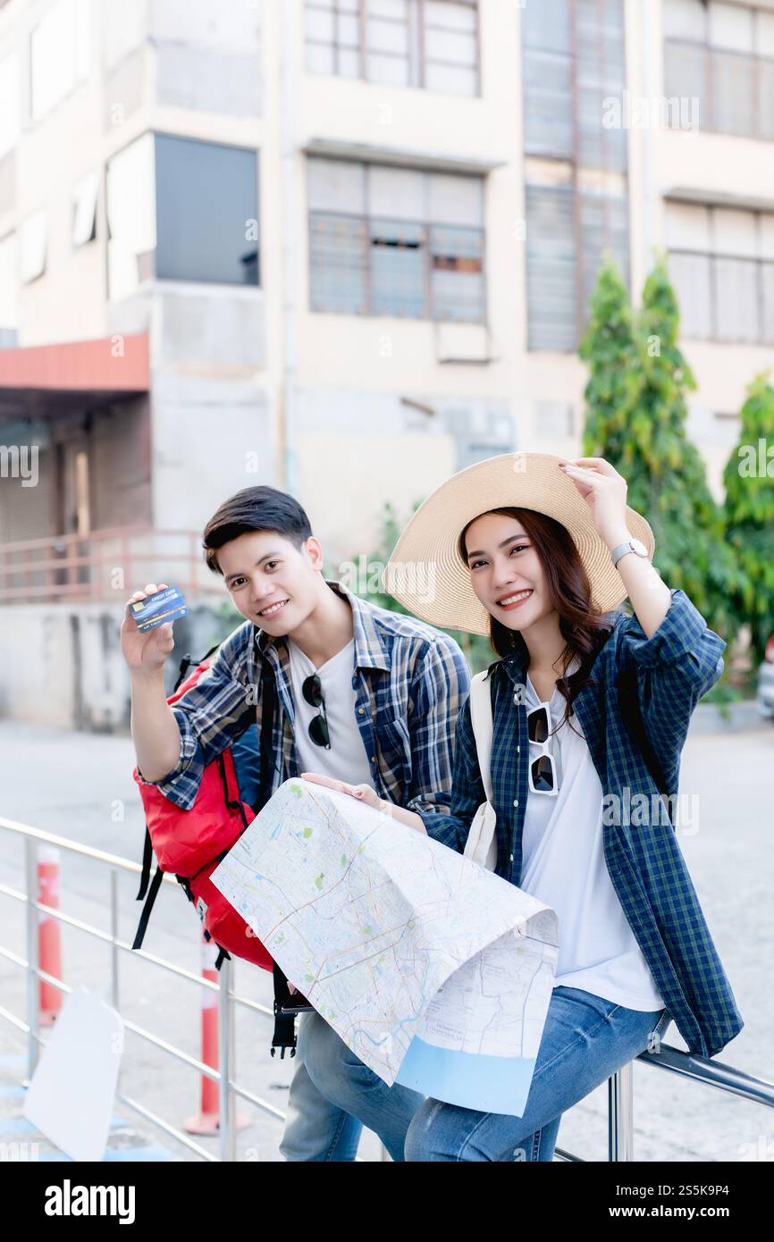 Young backpacker man holding paper map and pretty woman wear sombrero hold smartphone and ...