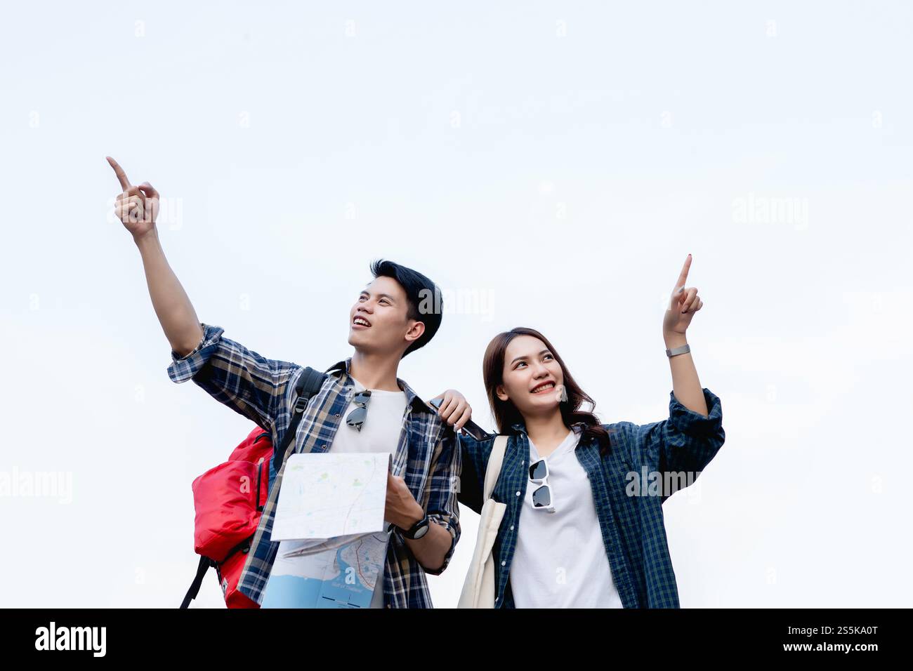 Portrait Cheerfully Young backpacker couple smile and pointing fingers ...