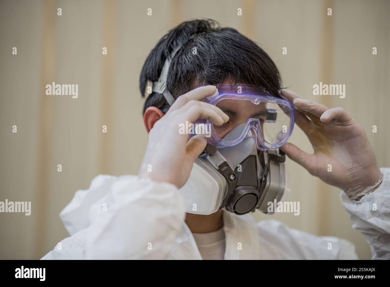 Man in personal protective equipment (PPE) suit wearing clear glasses ...