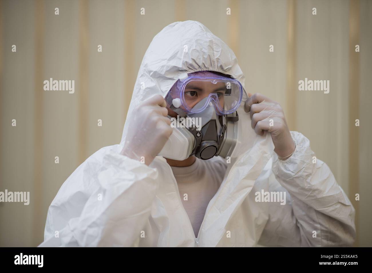Man in personal protective equipment (PPE) suit wearing clear glasses ...