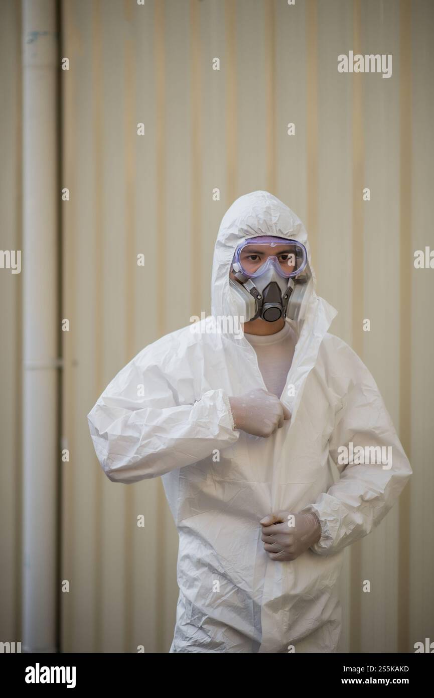 Man in personal protective equipment (PPE) suit wearing clear glasses ...