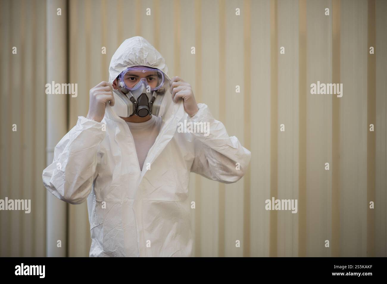 Man in personal protective equipment (PPE) suit wearing clear glasses ...