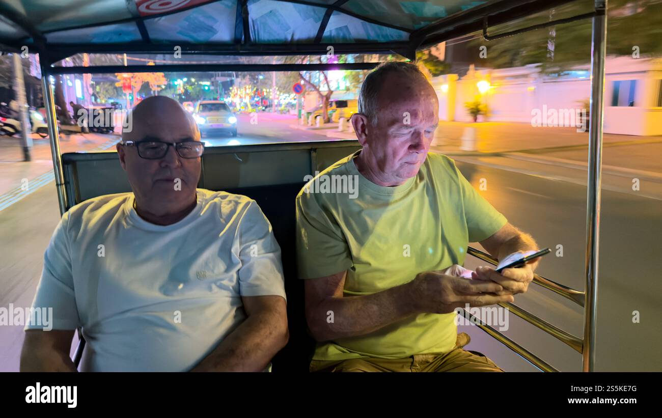 Two senior welsh males in the back of a tuk-tuk on the streets of Phnom ...