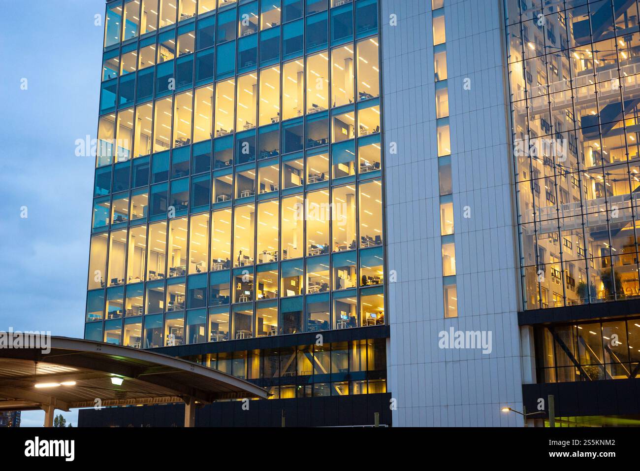 Large illuminated office building with people sitting behind their ...