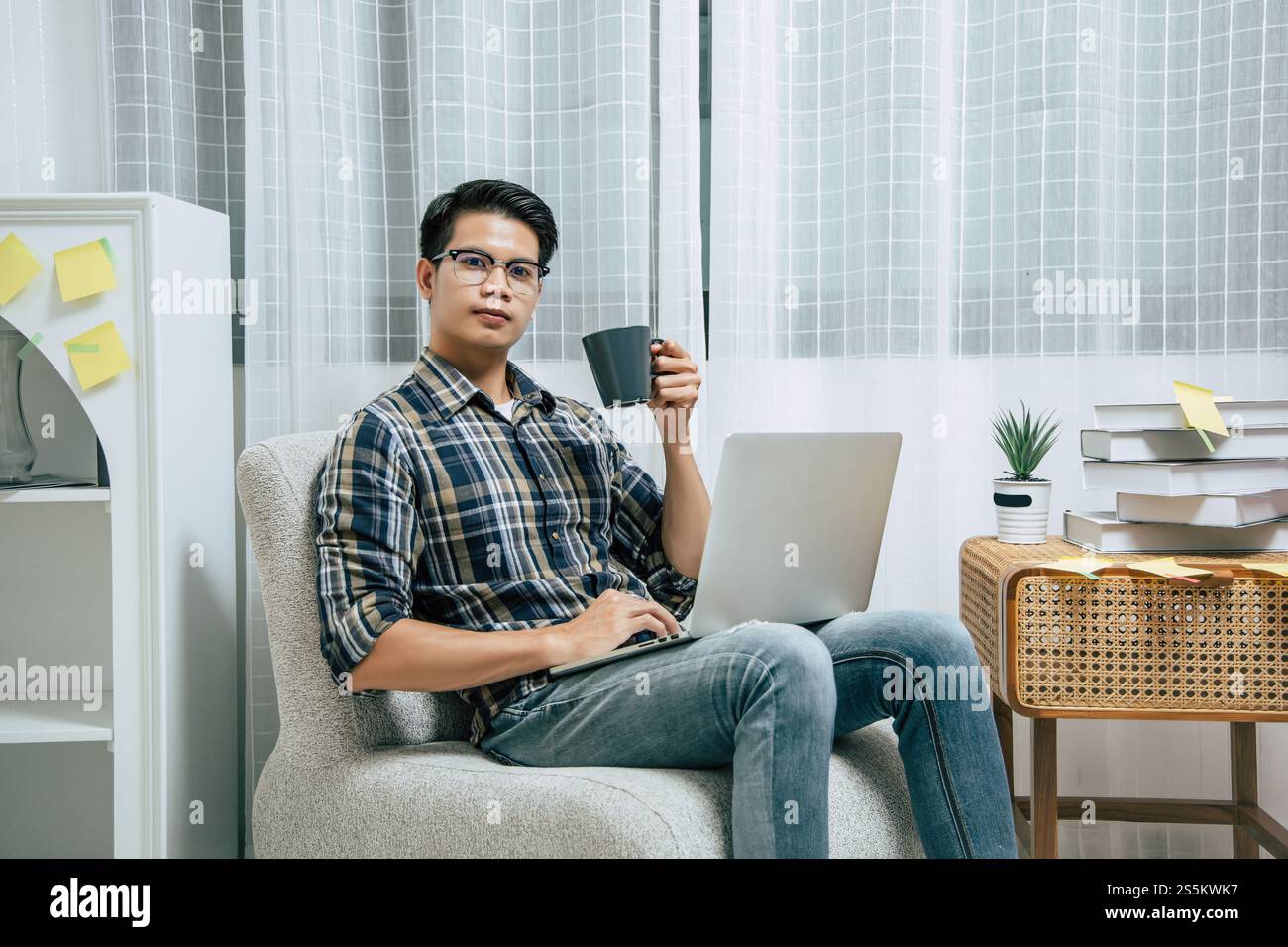 Portrait of smiling handsome man in glasses relaxing with coffee, using ...