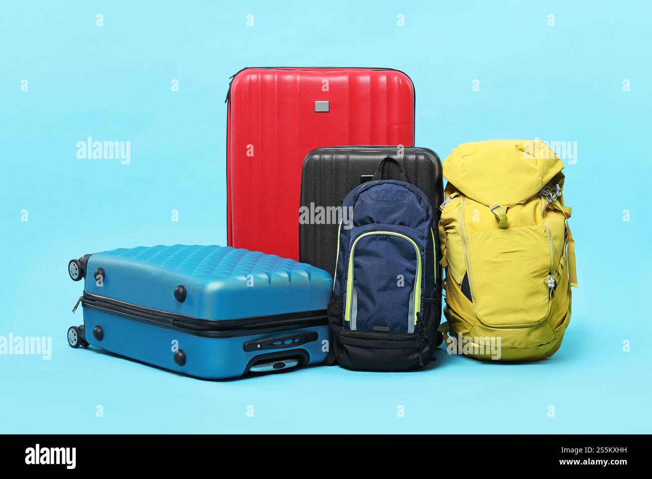 Colorful suitcases and backpacks on light blue background Stock Photo ...