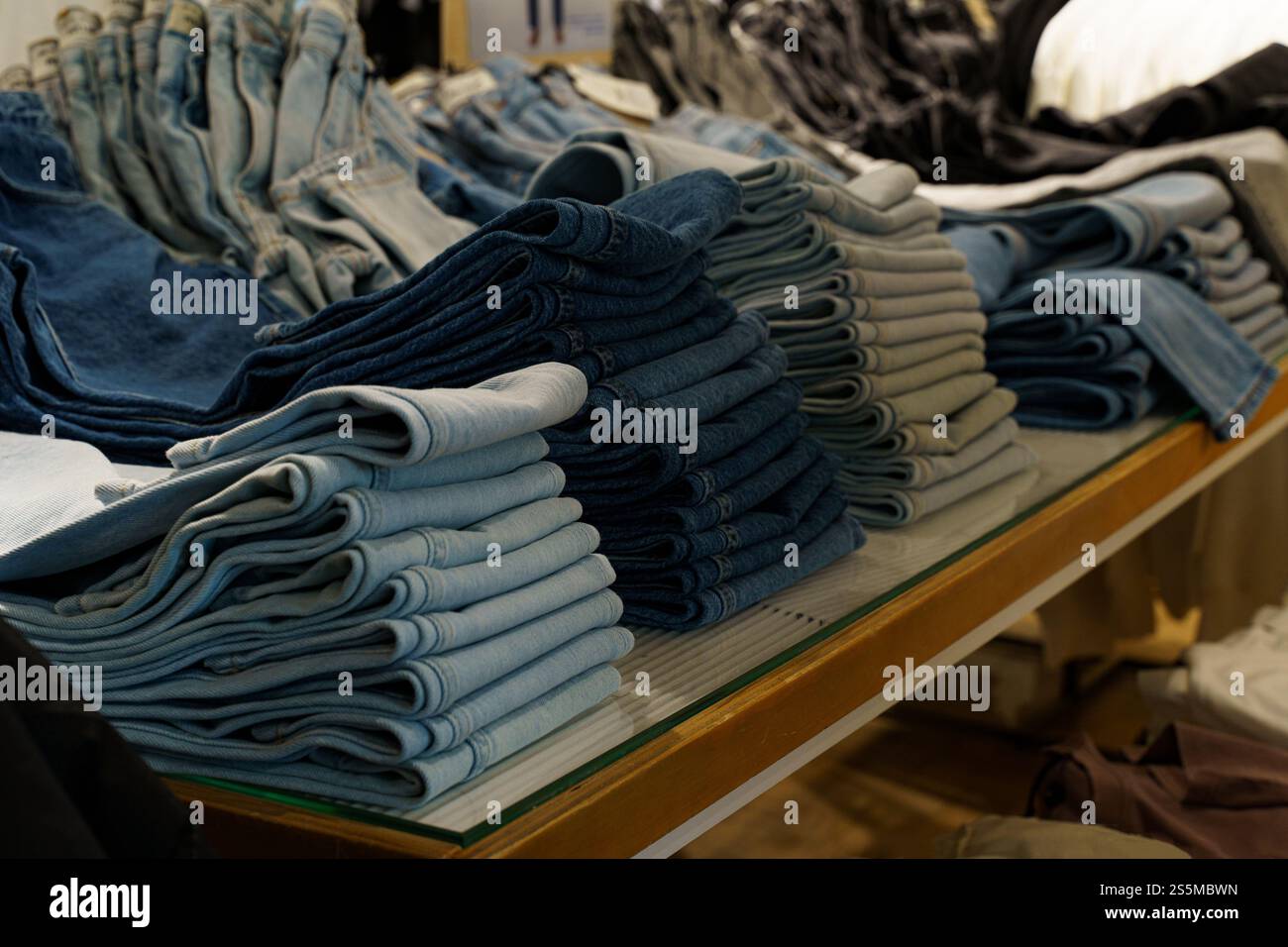Neatly stacked jeans in various shades of blue and gray create an ...