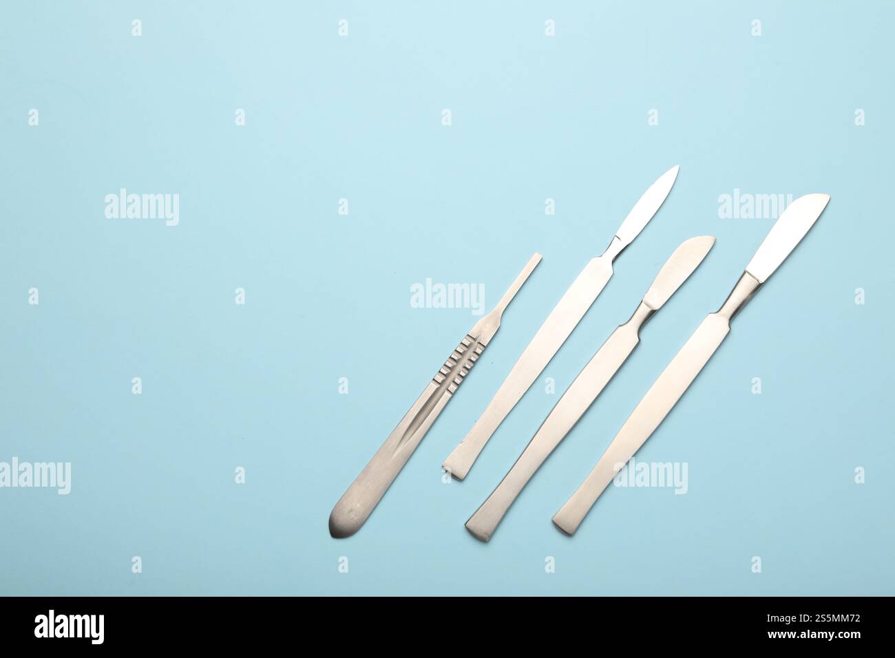 Different surgical scalpels on light blue background, flat lay. Space ...