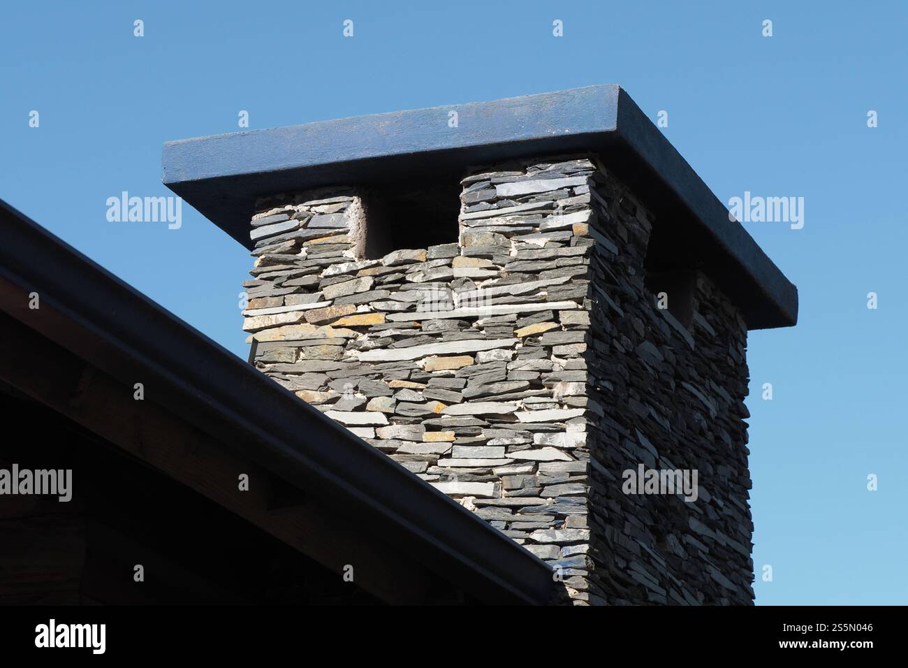Stone chimney atop rustic building under clear blue sky showcasing ...
