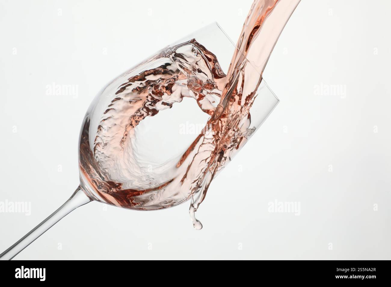 Pouring rose wine into glass on white background Stock Photo - Alamy