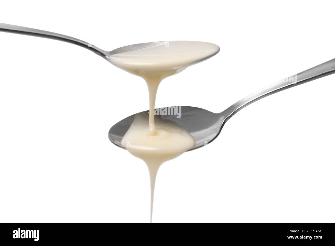 Condensed milk flowing down from spoons isolated on white Stock Photo ...