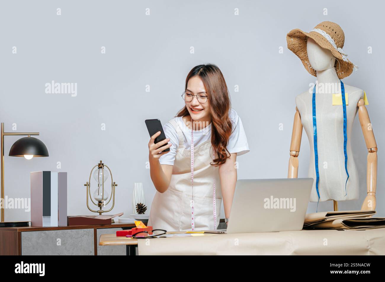 Beautiful young Asian fashion designer or tailor with working with ...