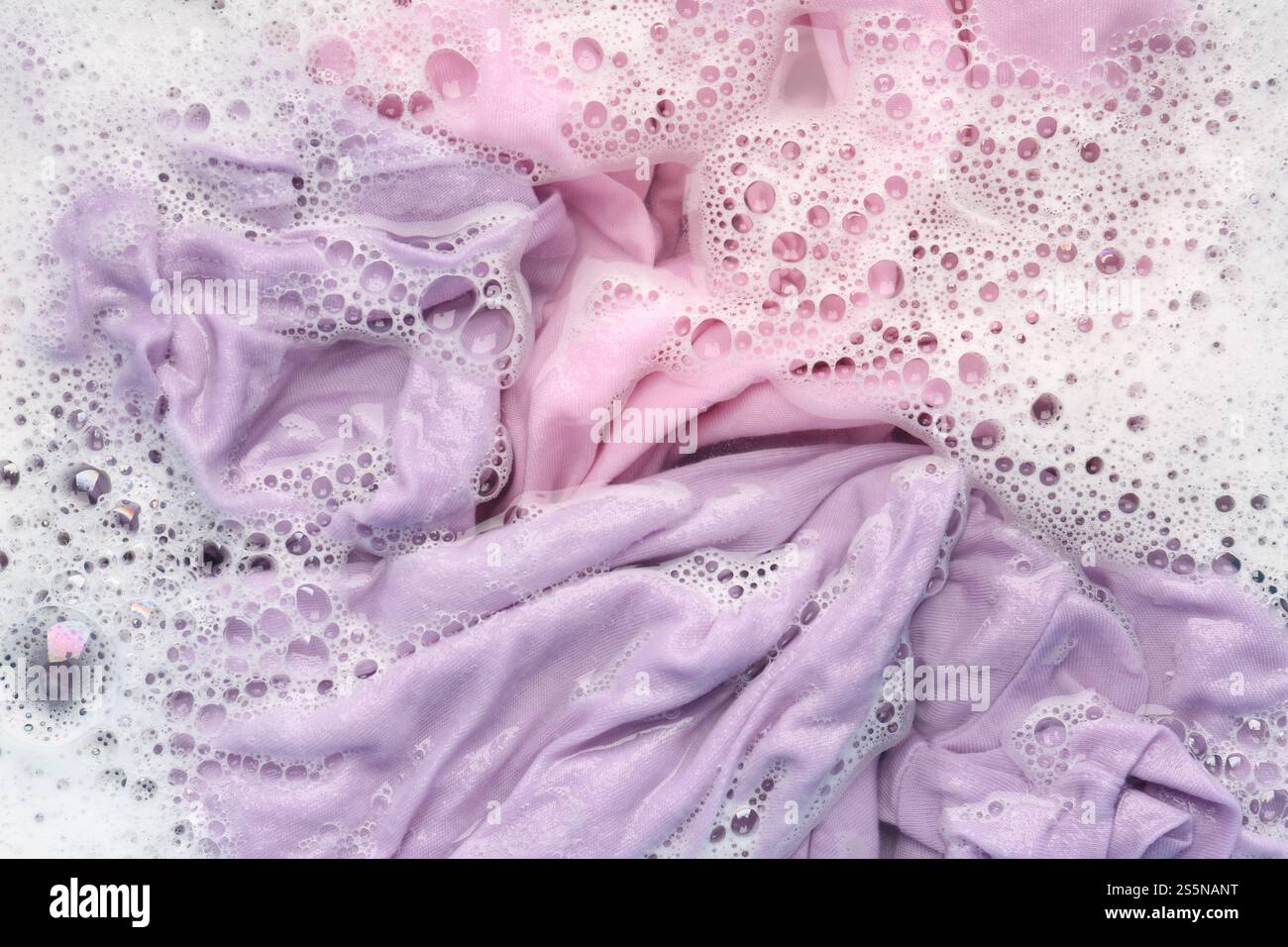 Colorful clothes soaked in water before washing, top view Stock Photo ...
