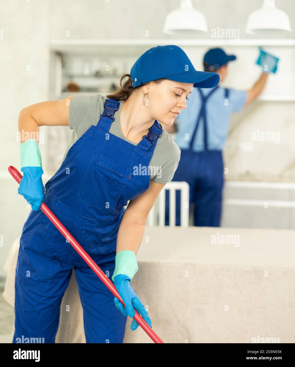 Young girl in blue uniform cleaning the floor in the kitchen Stock ...