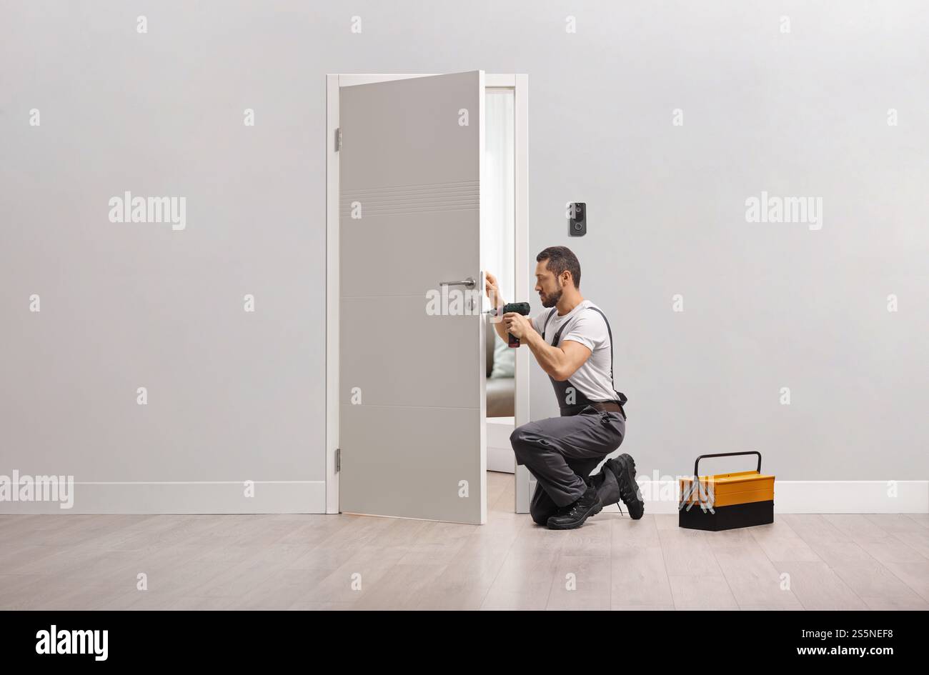 Repairman fixing a door with a drilling machine Stock Photo - Alamy
