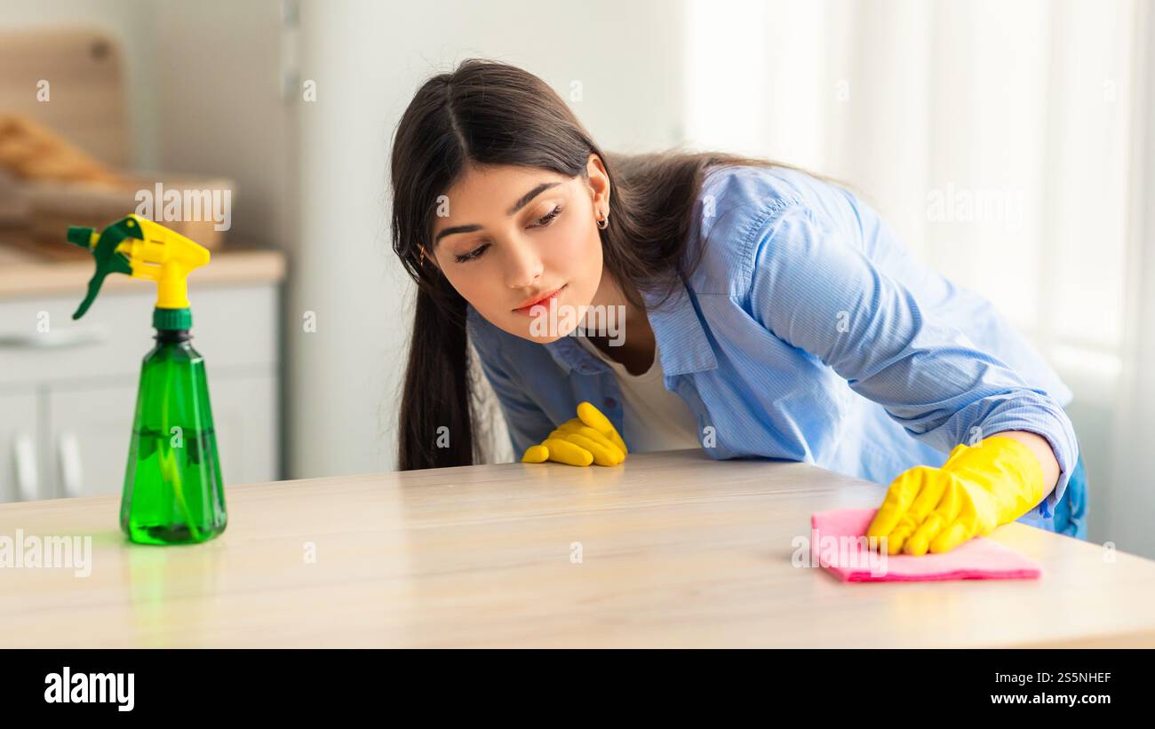 Closeup of focused young woman cleaning table with cloth Stock Photo ...
