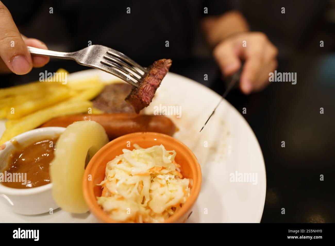 Man eating Grilled Meats stake from plate. hand holding knife and fork ...