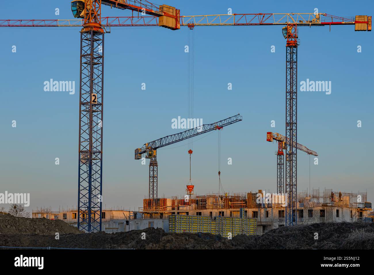 Tower cranes at a construction site with workers and unfinished ...