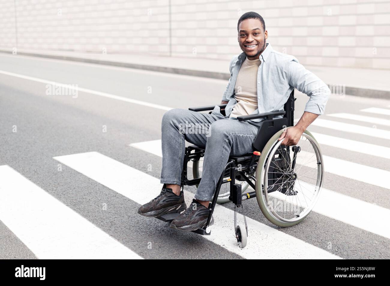 Full length of handicapped black man in wheelchair crossing street ...